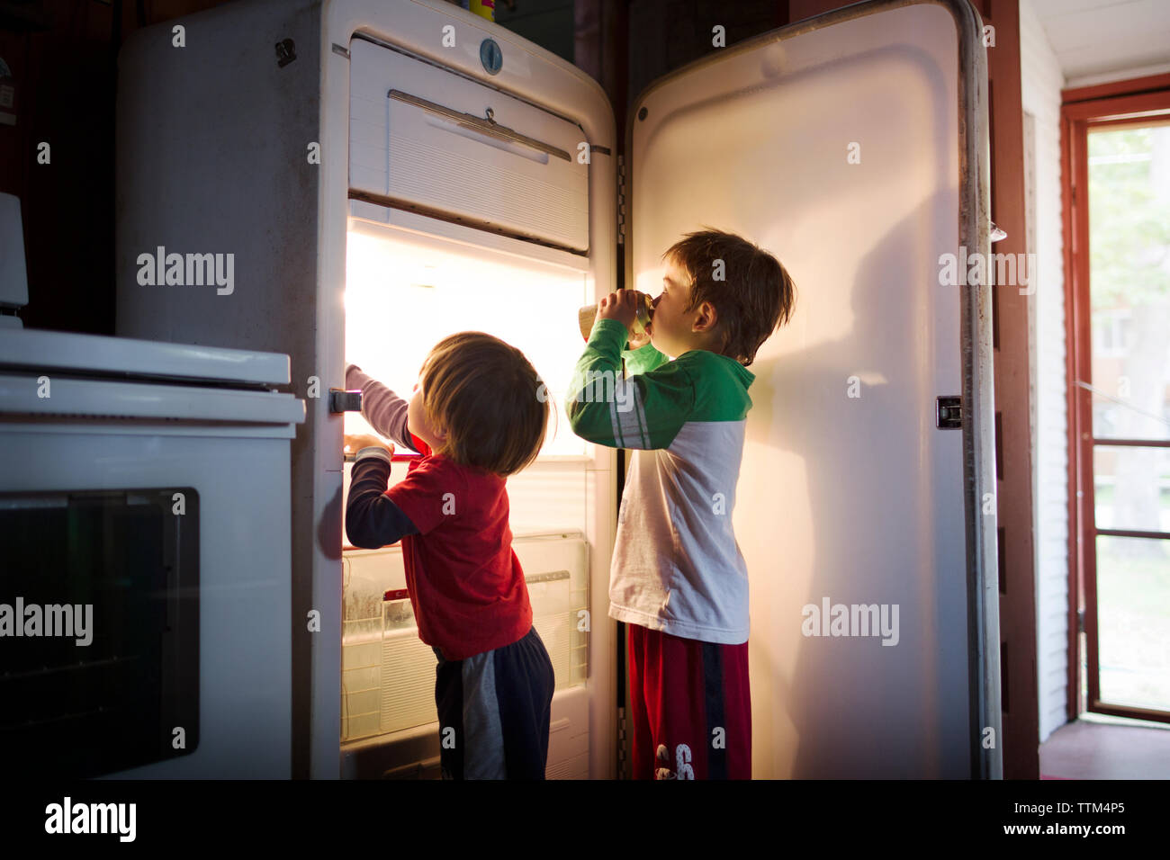 Boys taking food from fridge Stock Photo - Alamy