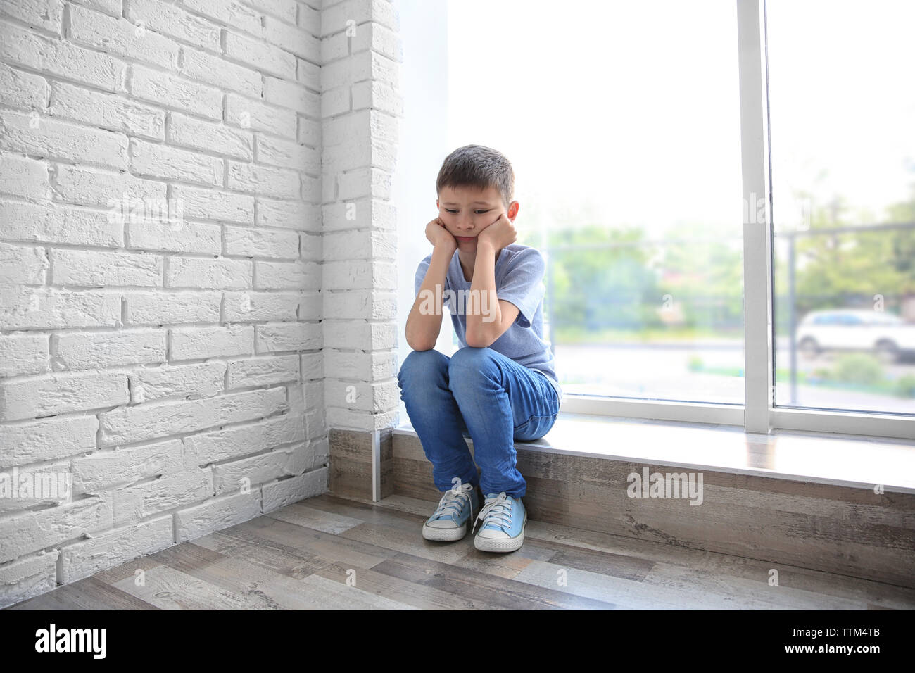 Sad boy sitting near window Stock Photo - Alamy