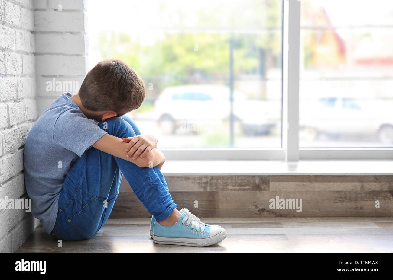 Sad boy sitting near window Stock Photo - Alamy