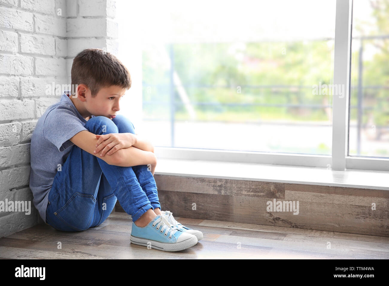 Sad boy sitting near window Stock Photo - Alamy
