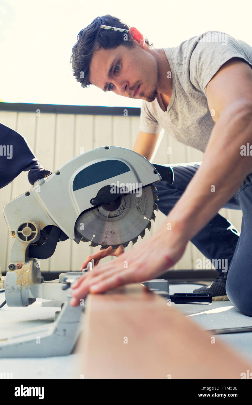 Man cutting wooden plank with circular saw in backyard Stock Photo - Alamy