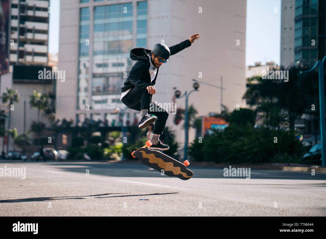 Full length of man performing stunt while skateboarding on road in city ...
