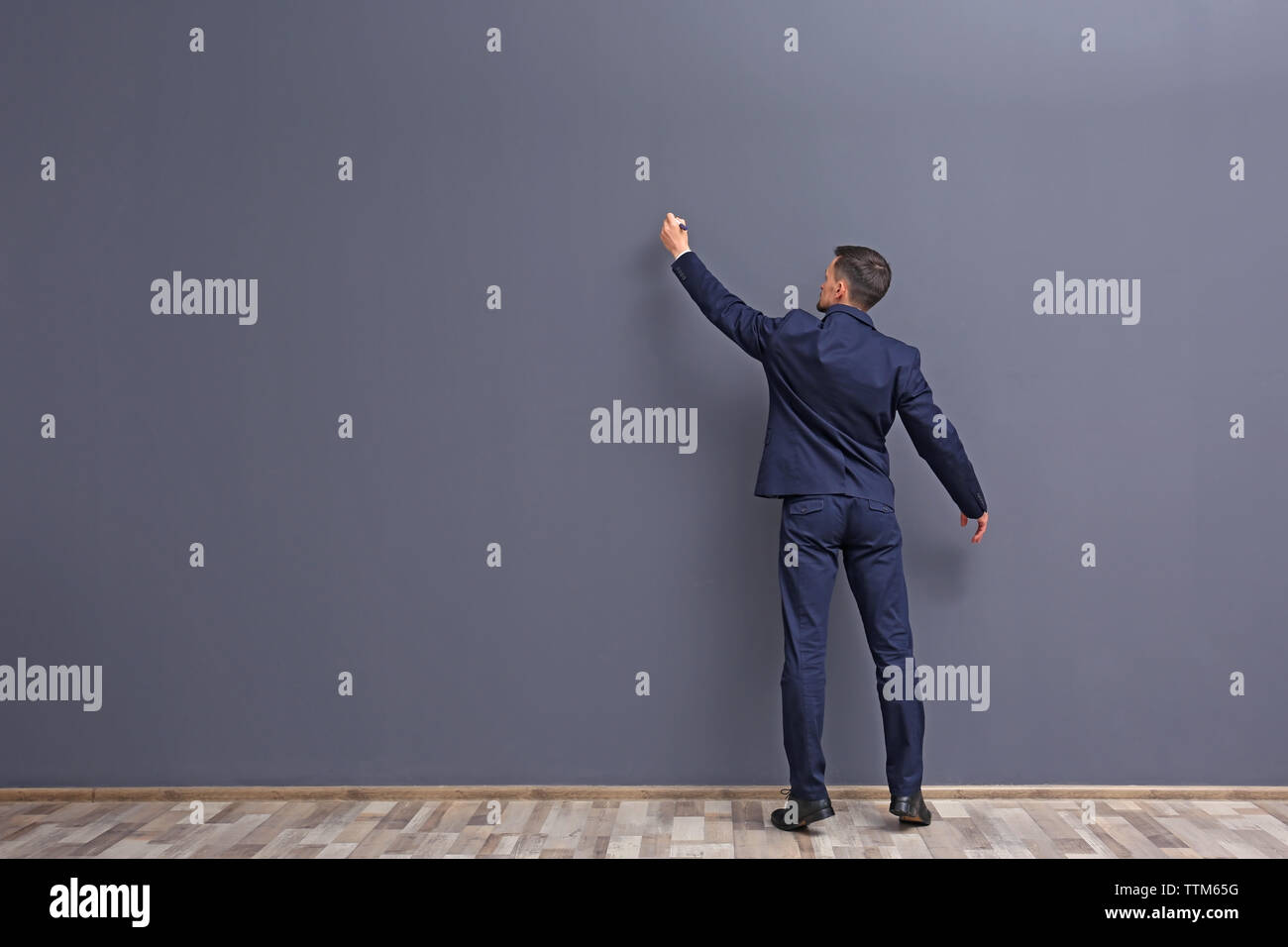 Man writing something on grey wall Stock Photo - Alamy