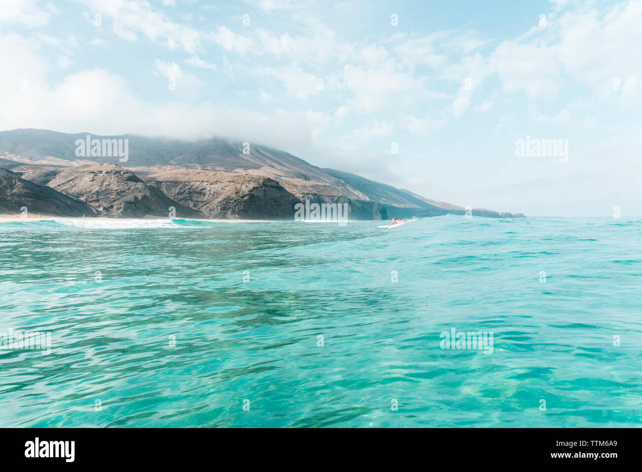 Mid distance view of man surfing in sea against cloudy sky Stock Photo ...
