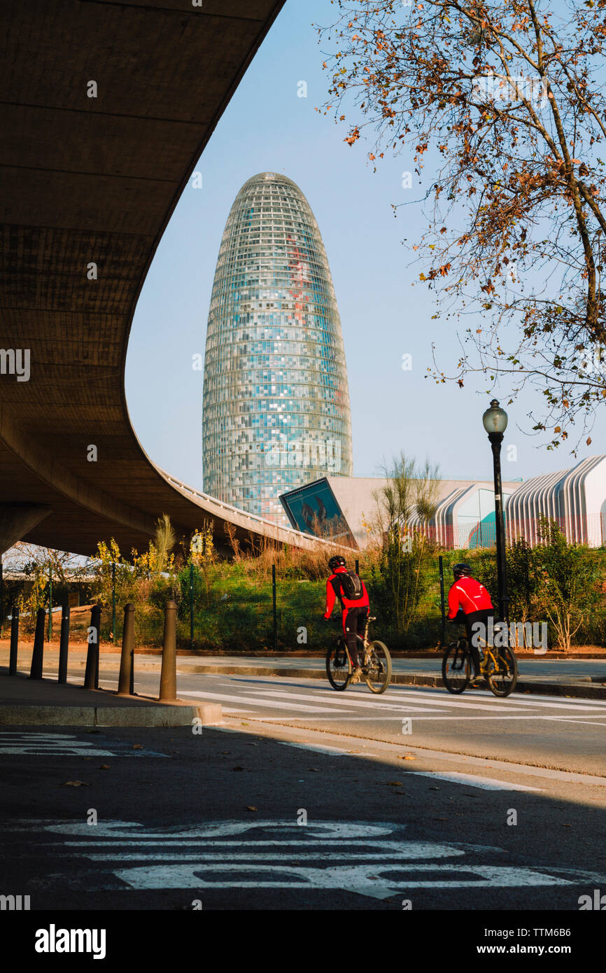 Low angle view of friends cycling against Torre Agbar Stock Photo - Alamy