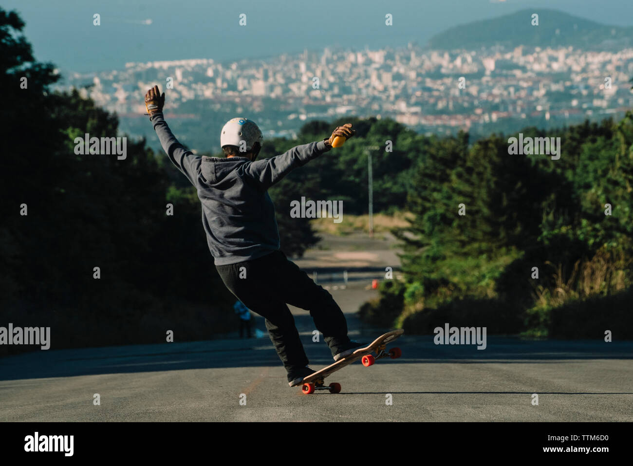 Rear view of man skateboarding on road against cityscape Stock Photo ...