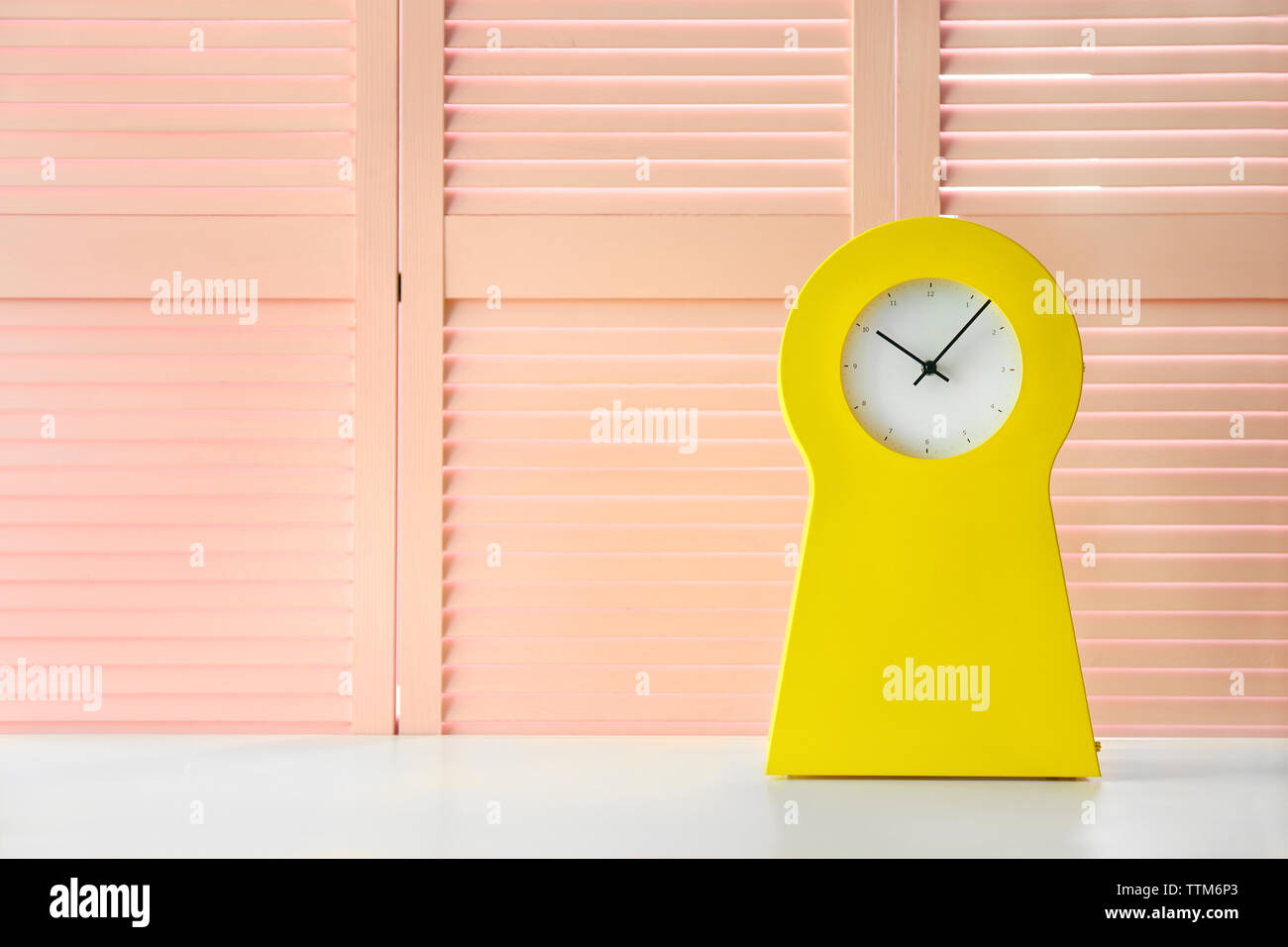 Stylish clock on pink folding screen background Stock Photo - Alamy