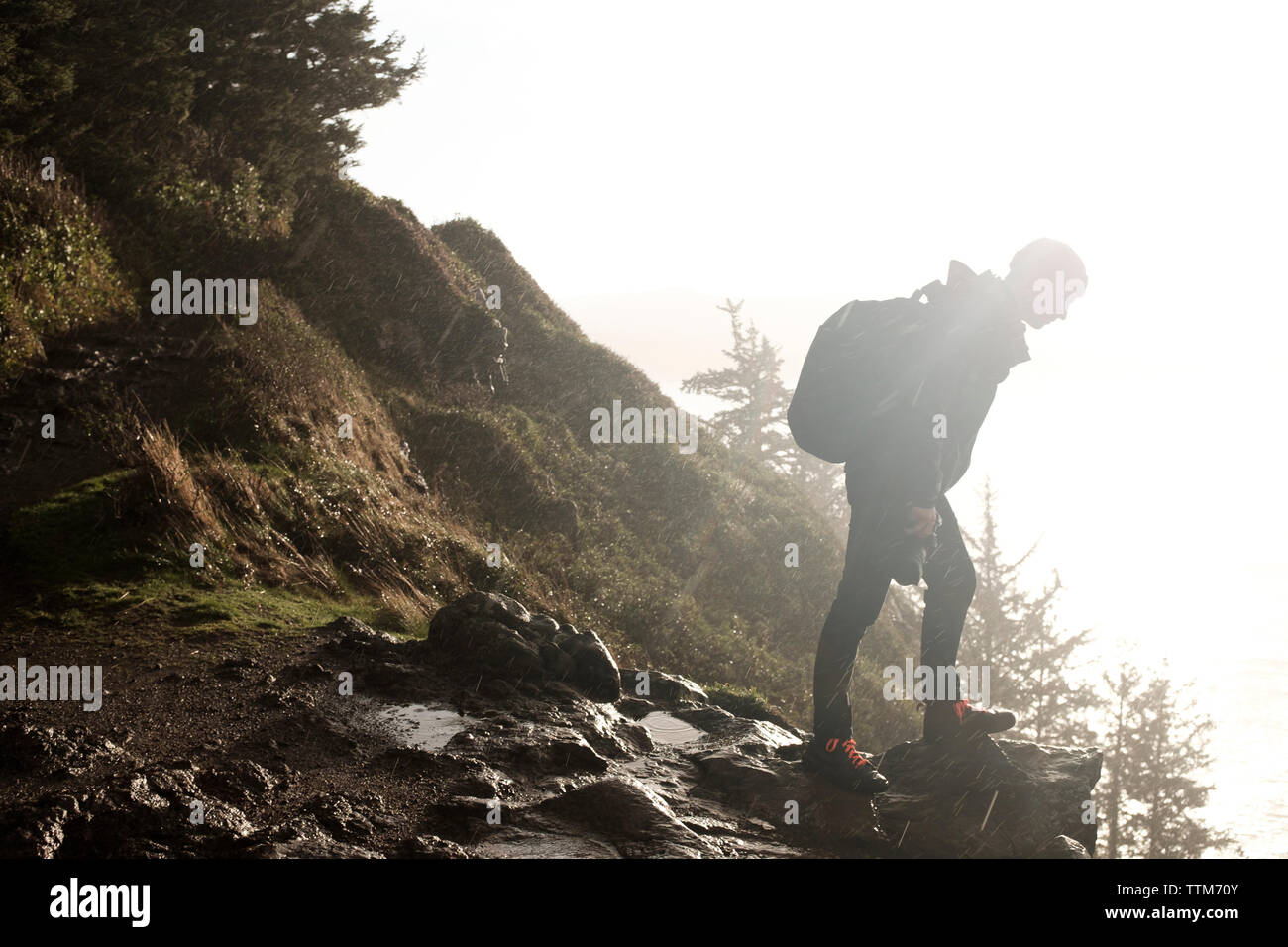 Side view of hiker with backpack standing on rocks against clear sky ...