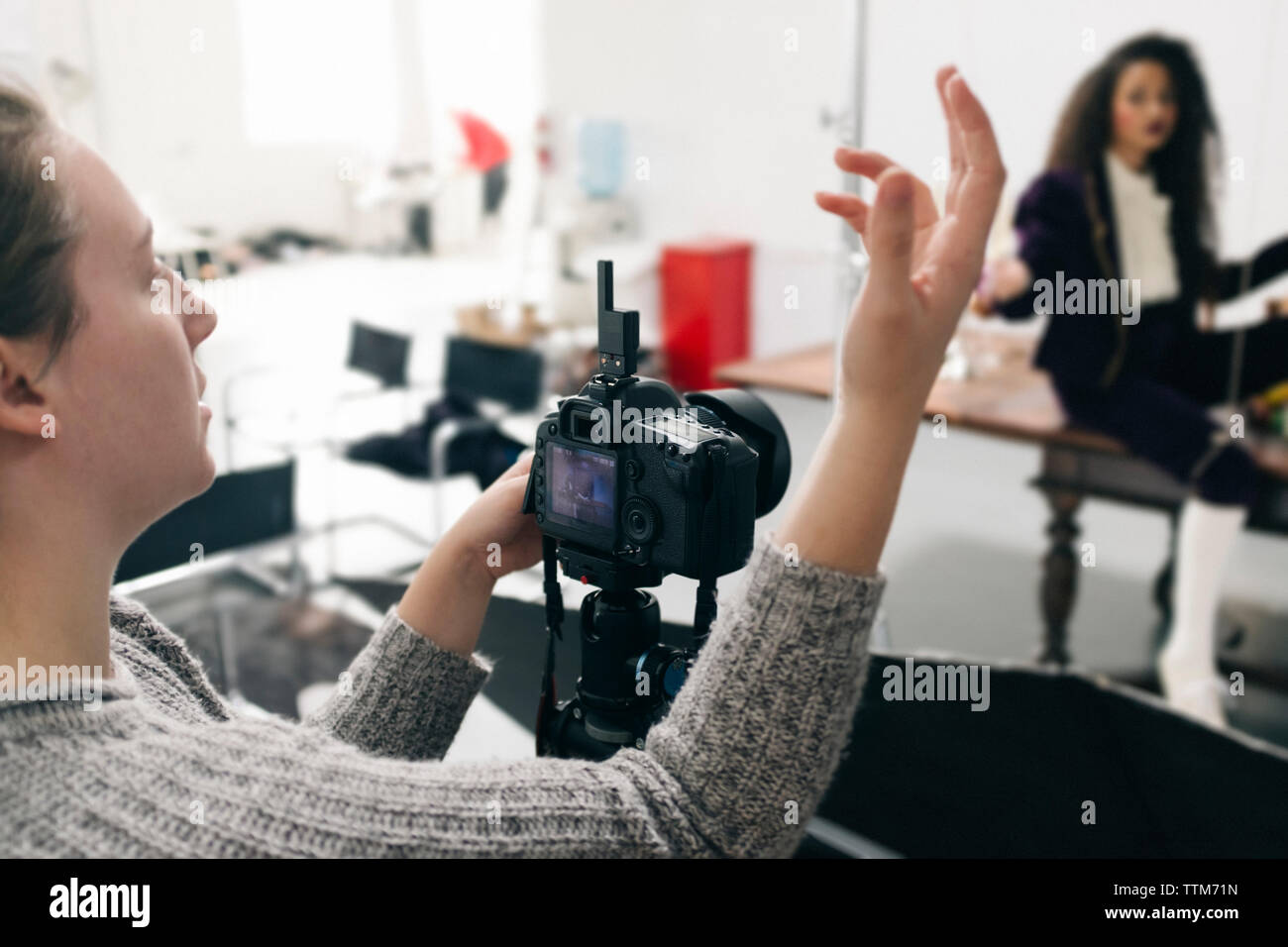 Photographer talking to female model while photographing in studio ...