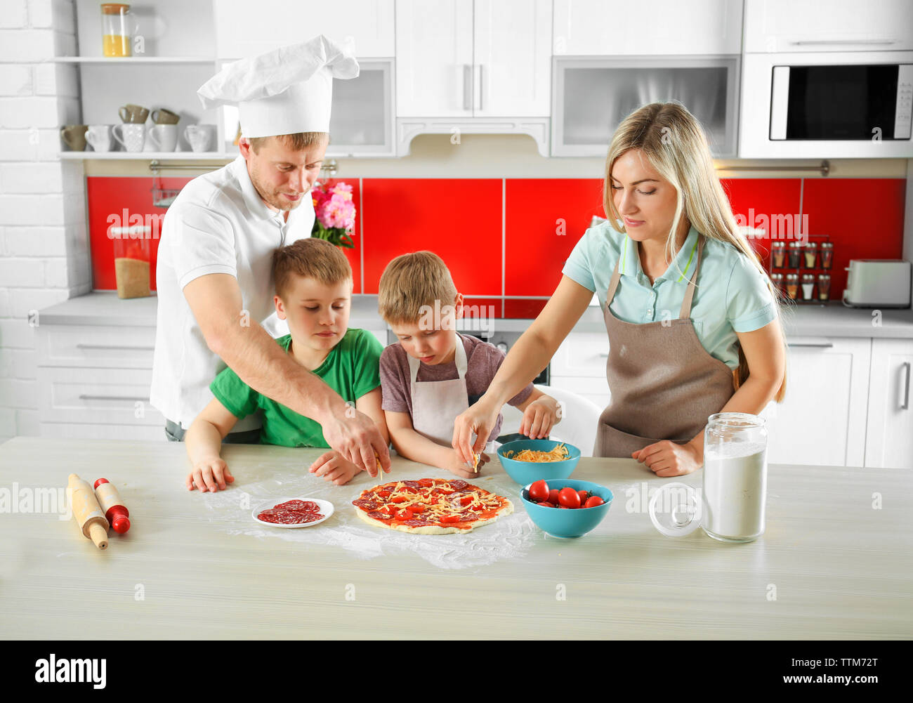Happy family making pizza in kitchen Stock Photo - Alamy