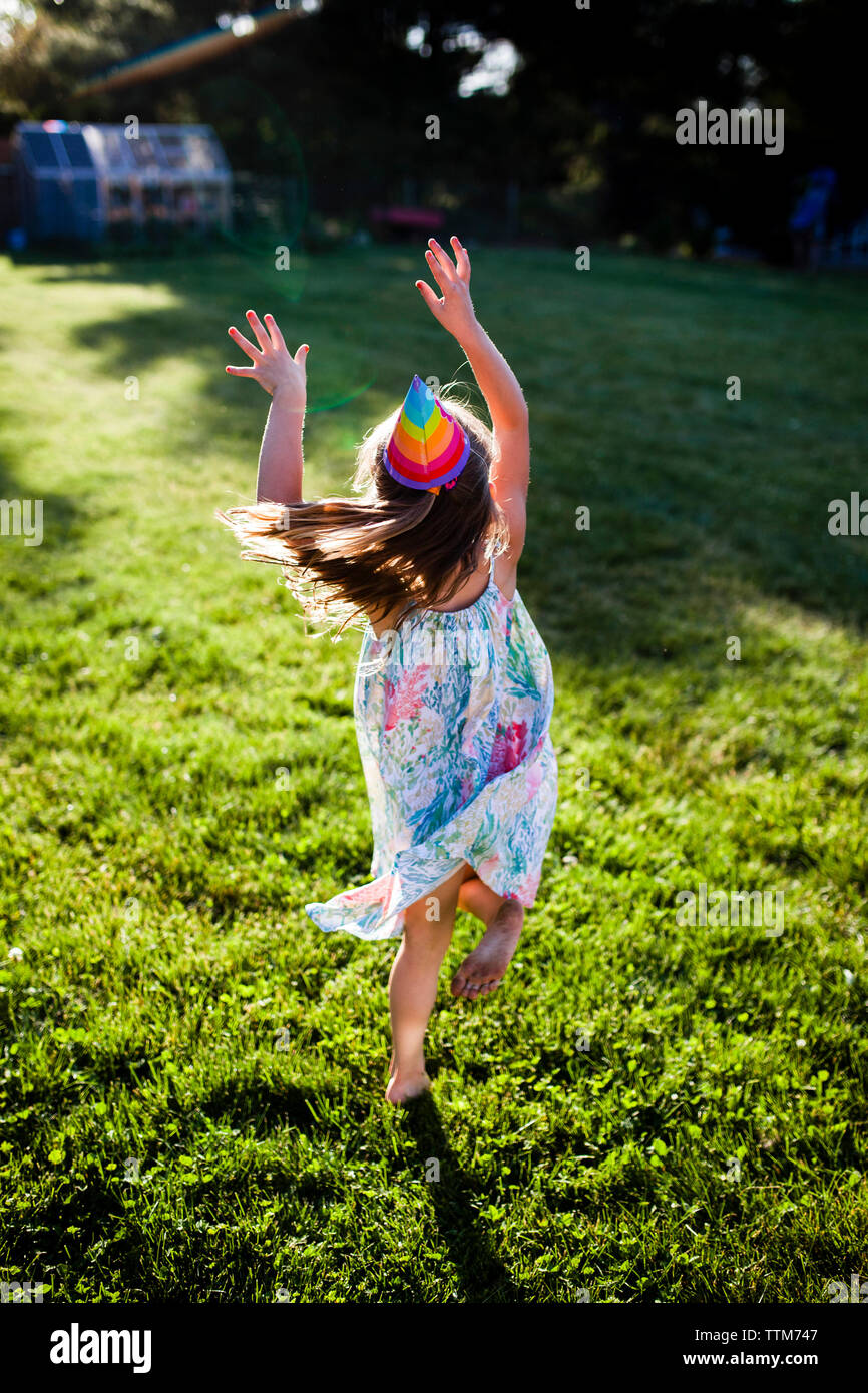 Cheerful girl in party hat jumping on grassy field at backyard Stock ...
