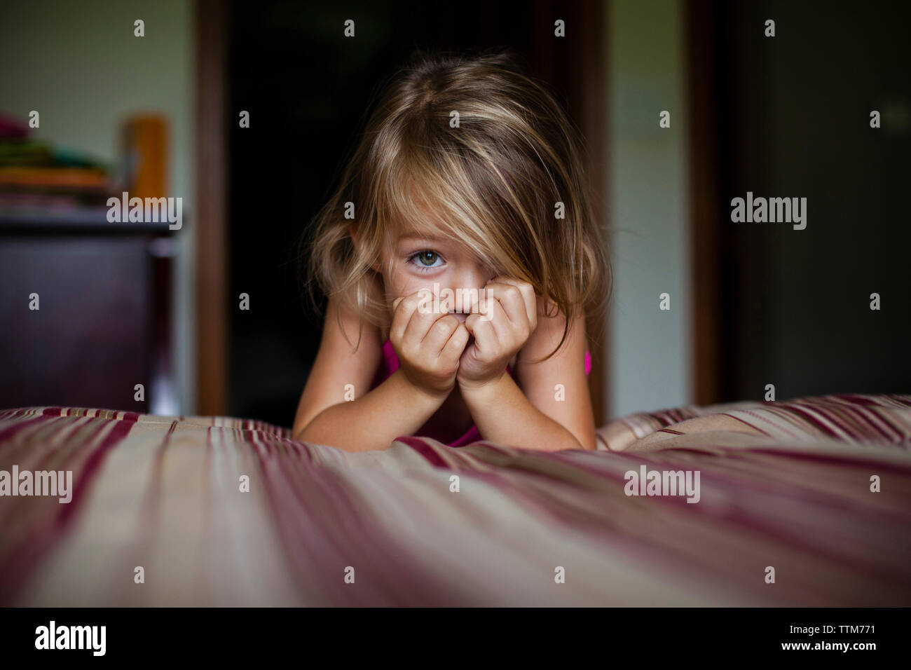 Portrait of cute girl leaning on bed at home Stock Photo - Alamy
