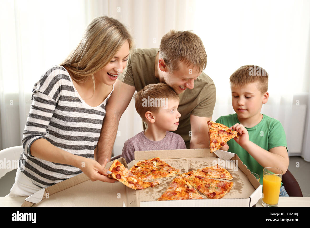 Happy lovely family eating pizza Stock Photo - Alamy