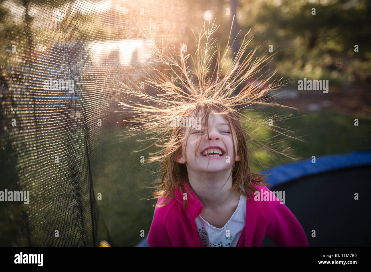 High angle view of cheerful girl jumping on trampoline in backyard ...
