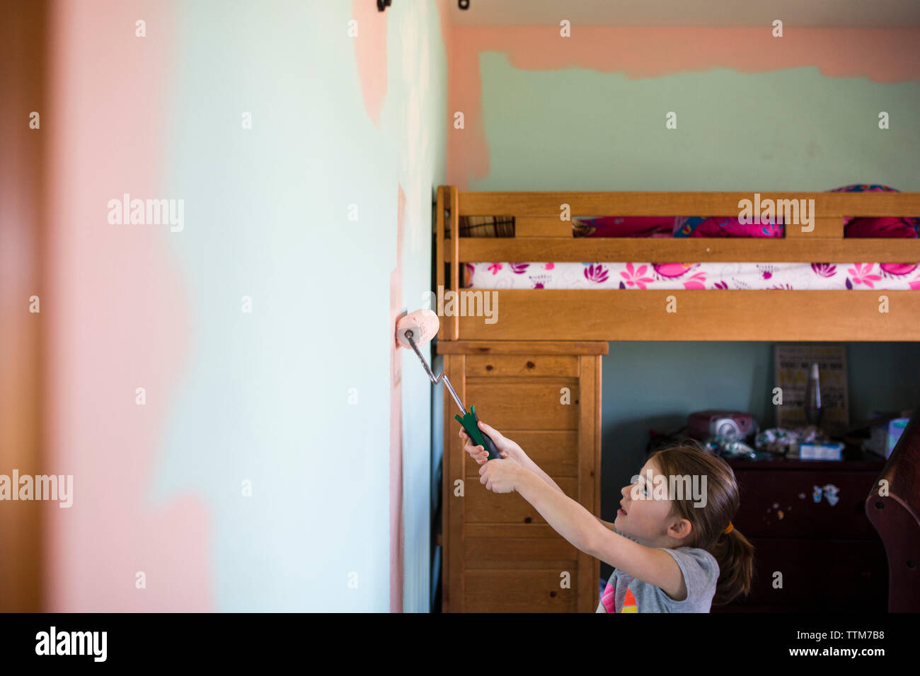 Side view of girl painting wall at home Stock Photo - Alamy