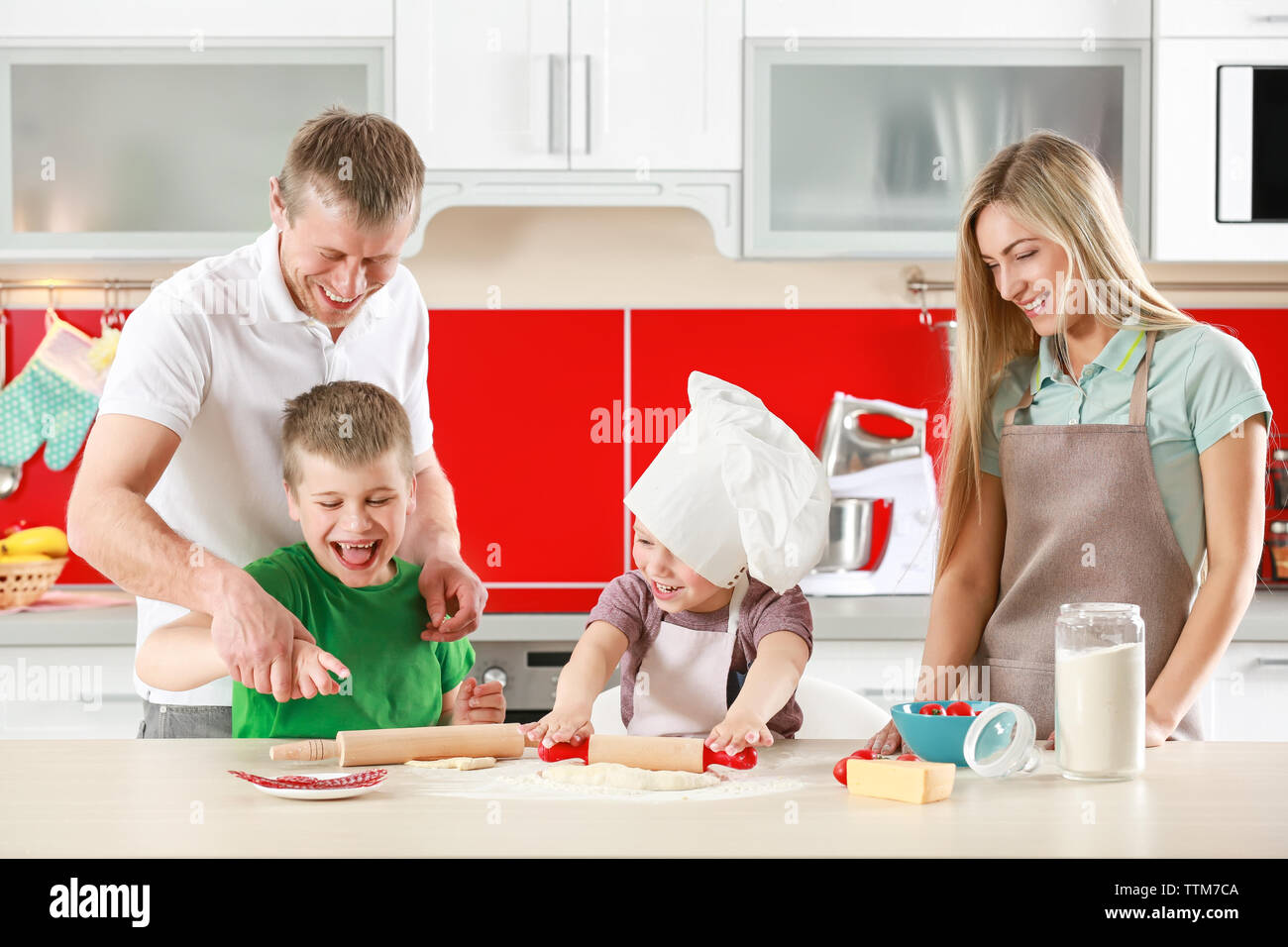 Happy family making pizza in kitchen Stock Photo - Alamy