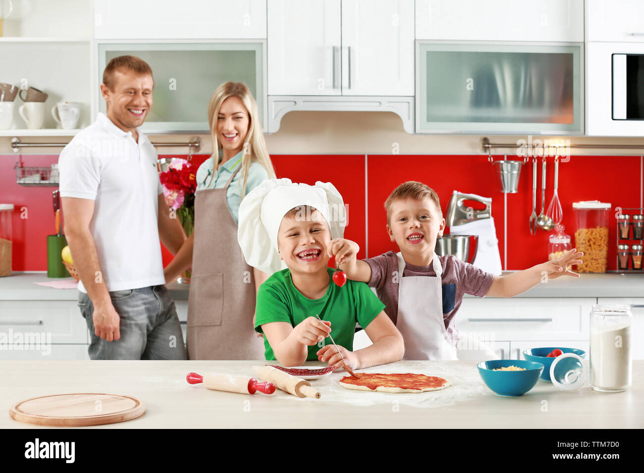 Happy family making pizza in kitchen Stock Photo - Alamy