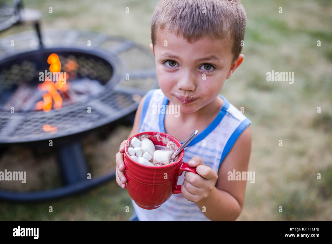 High angle portrait of boy having marshmallows in coffee while standing ...