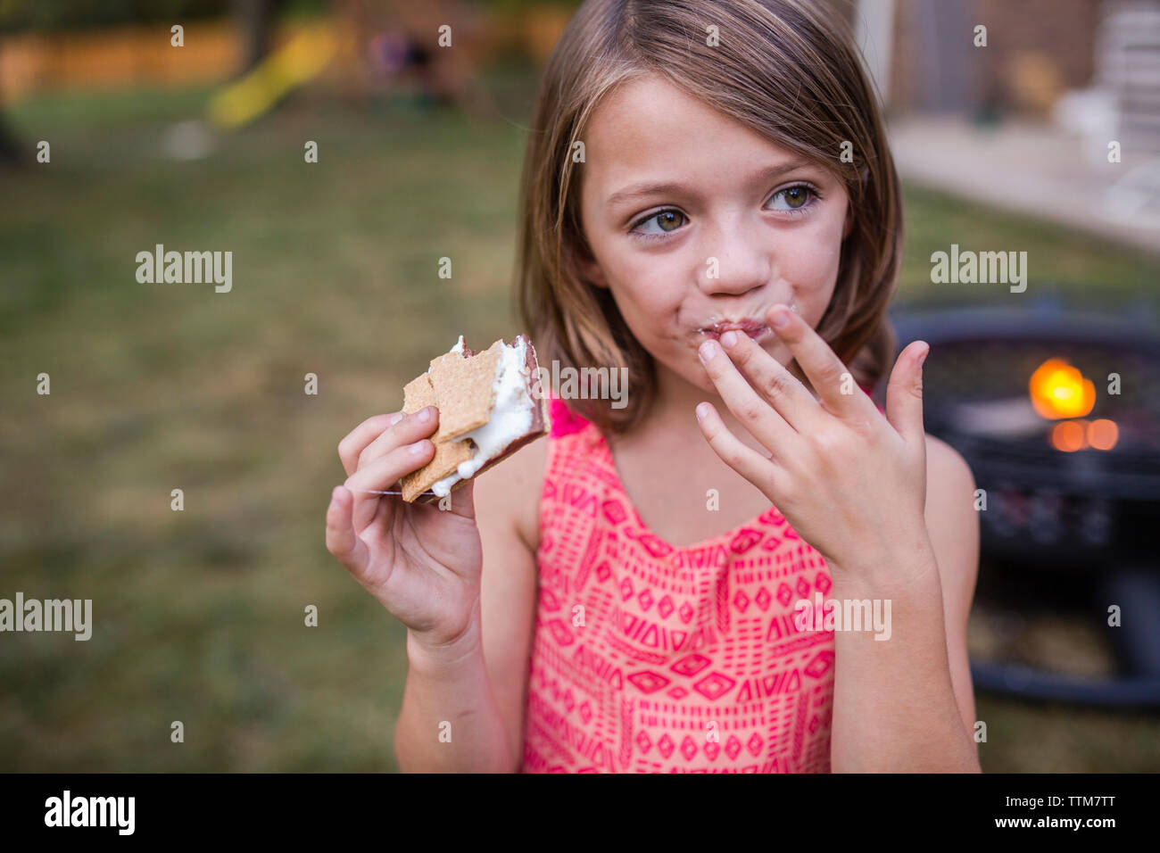 Close-up of girl eating sweet food while standing at yard Stock Photo ...