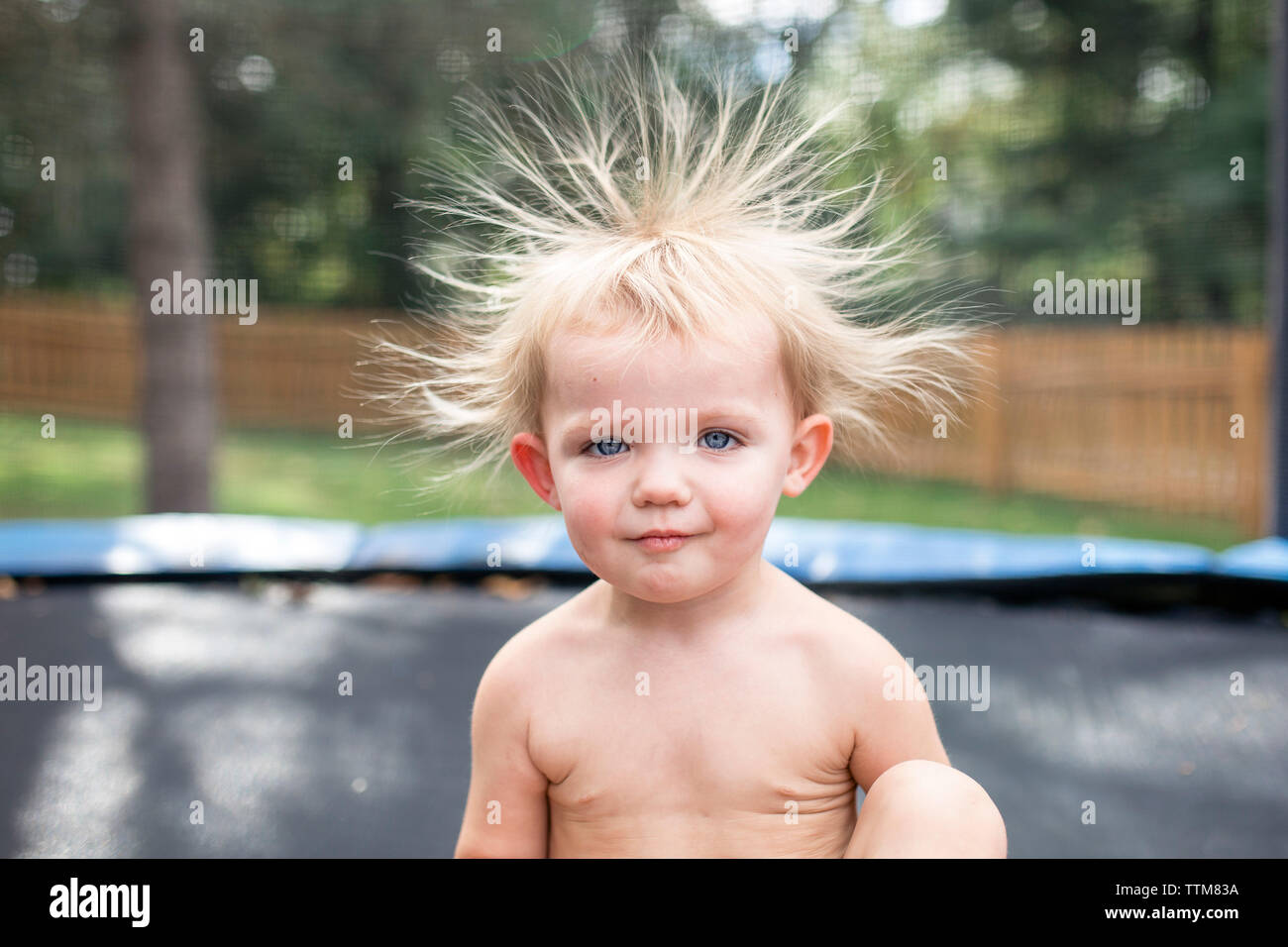 Toddler girl sitting on trampoline with wild static hair Stock Photo ...