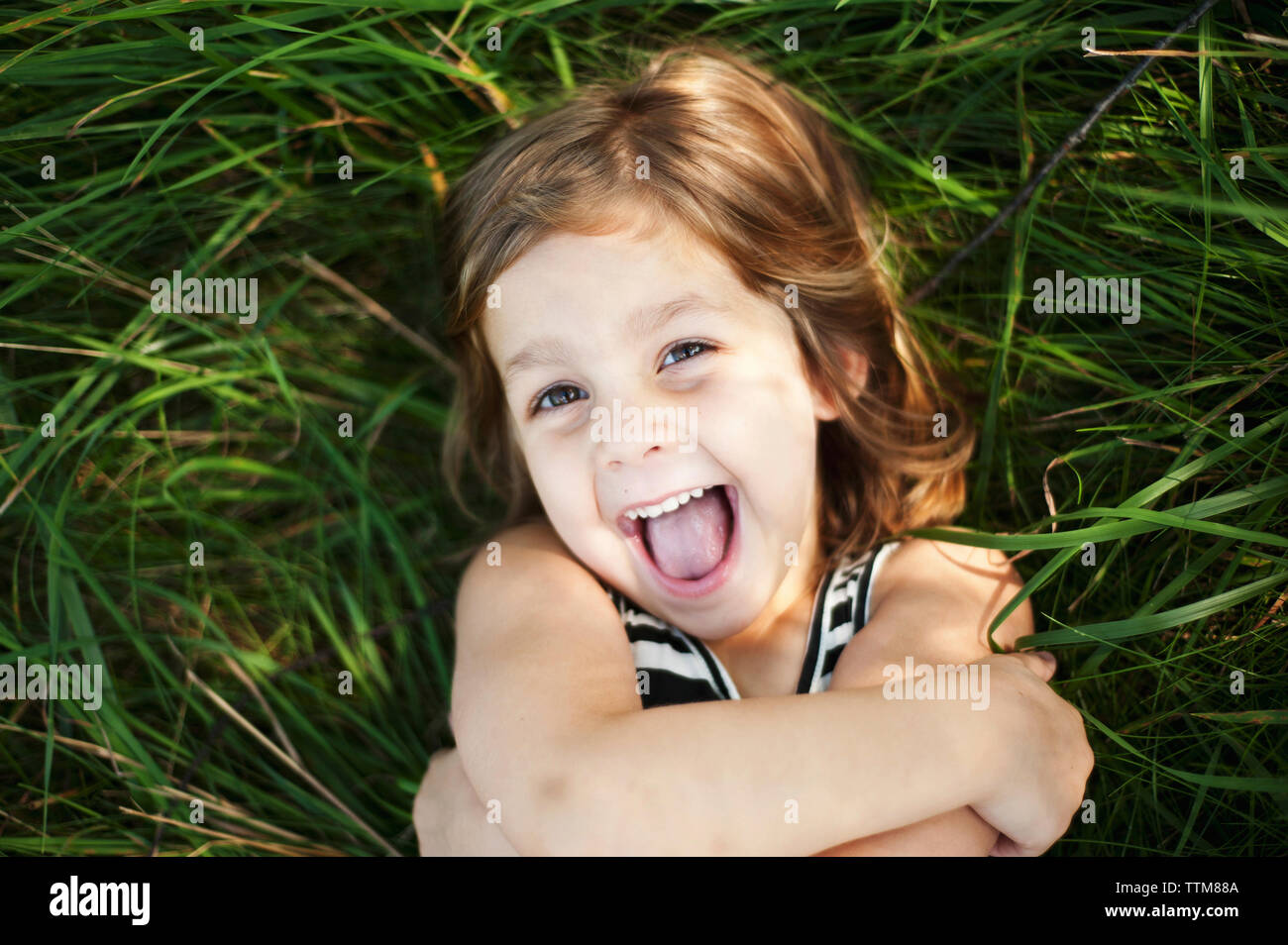 High angle portrait of happy girl lying on grassy field at park Stock ...