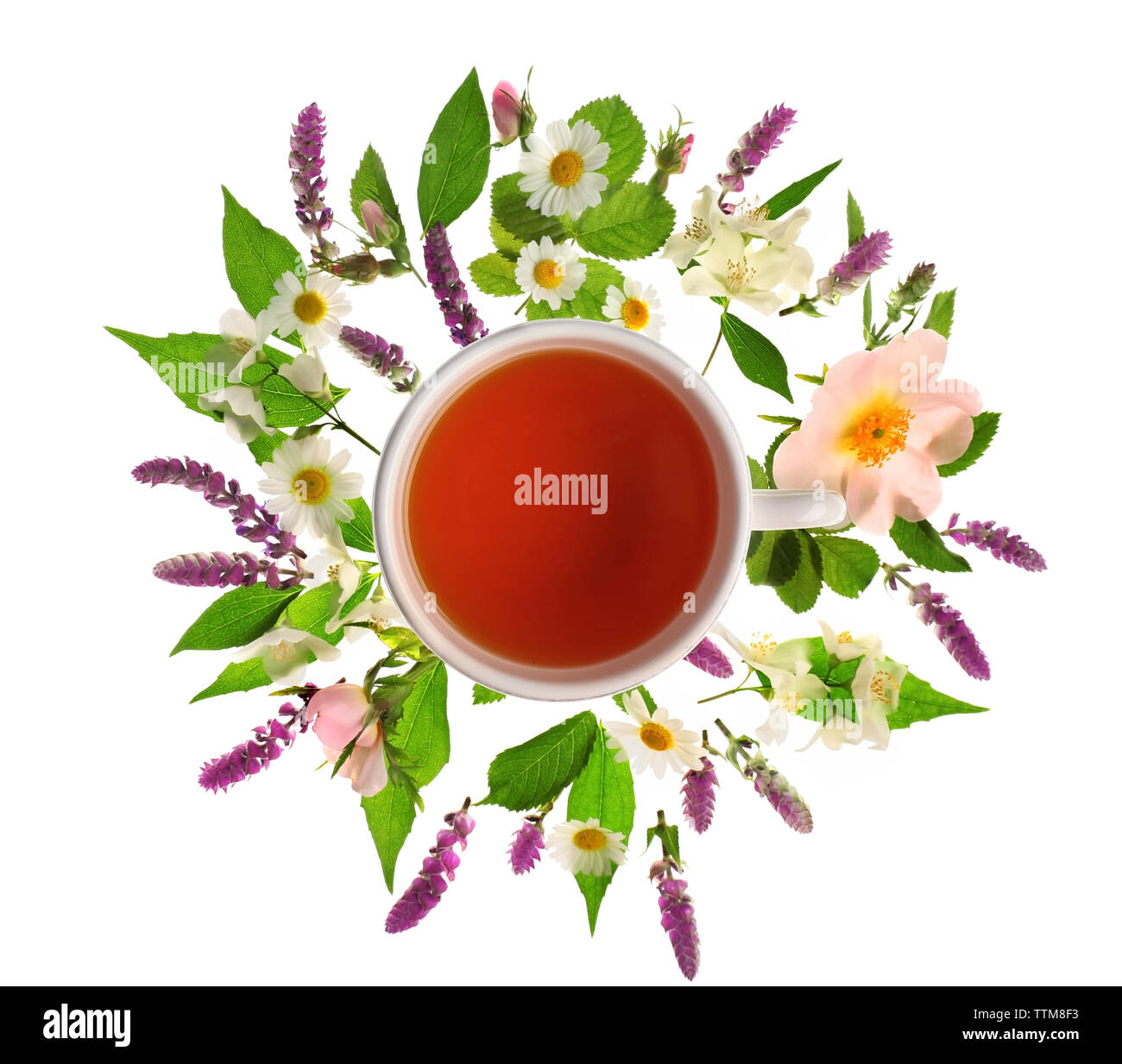 Cup of tea with fresh flowers lying around on white background Stock ...