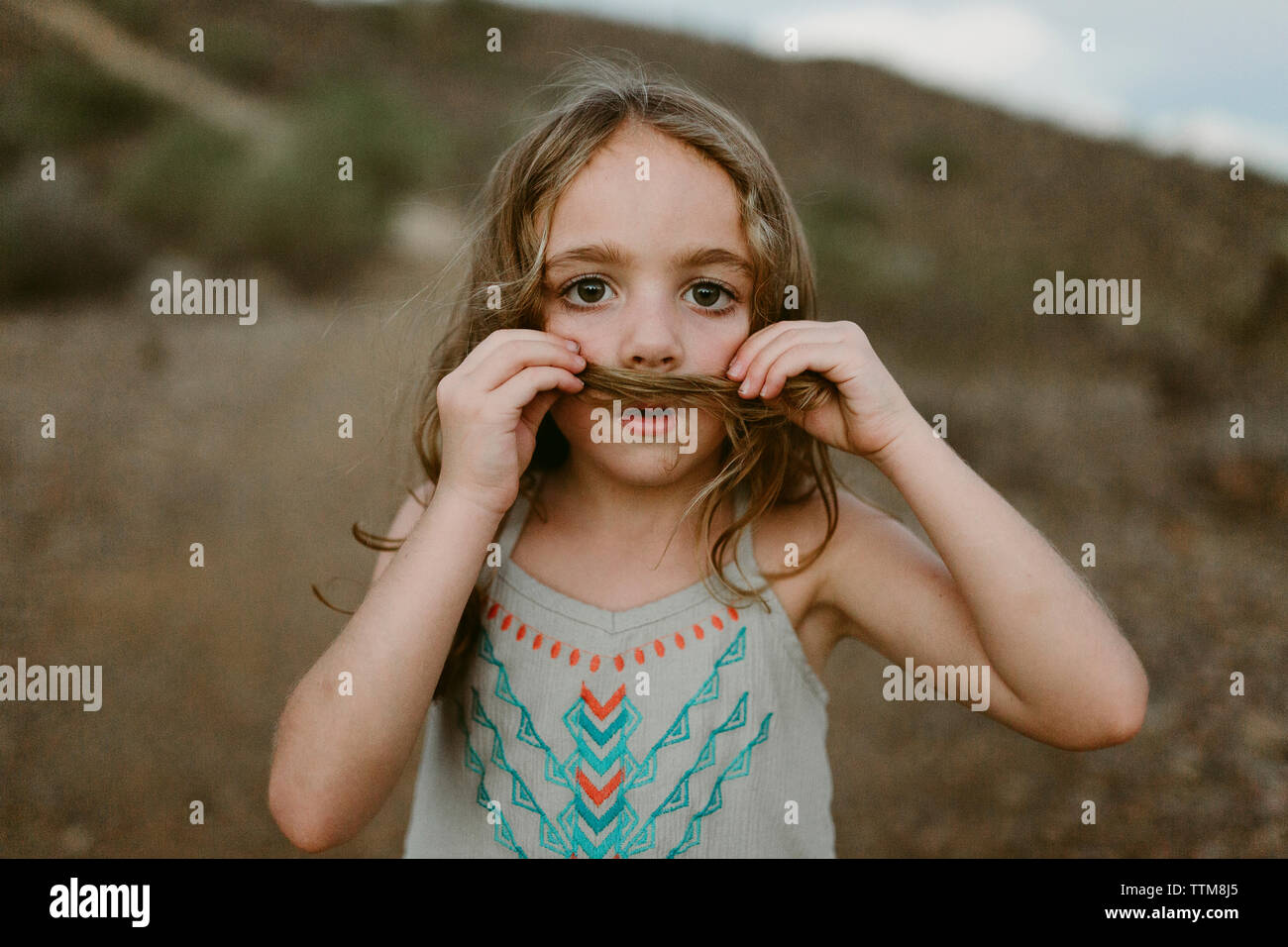 Portrait of cute girl making mustache with her hair Stock Photo - Alamy