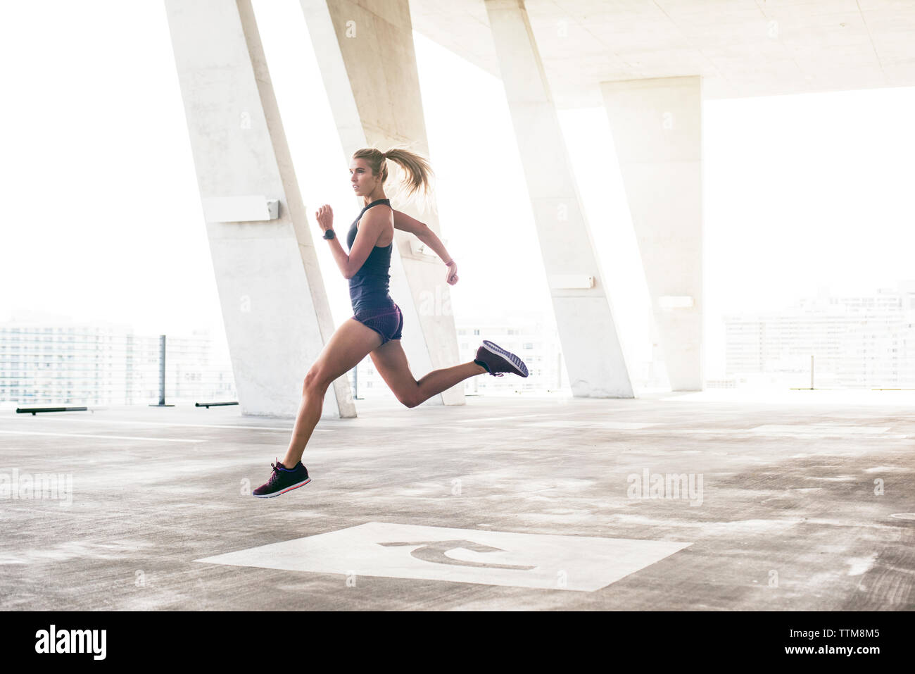 Confident young woman running at parking lot Stock Photo - Alamy