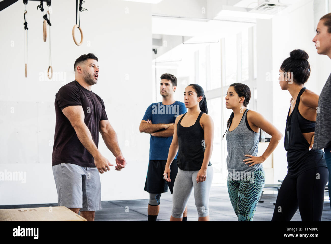 Athletes listening to instructor explaining in crossfit gym Stock Photo ...