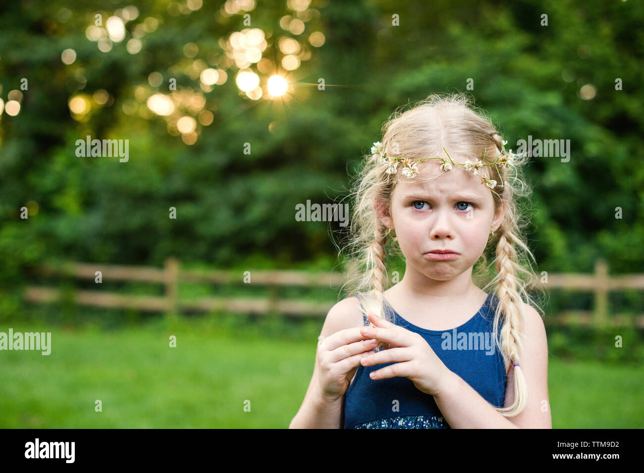 Sad girl looking away while standing in backyard Stock Photo - Alamy