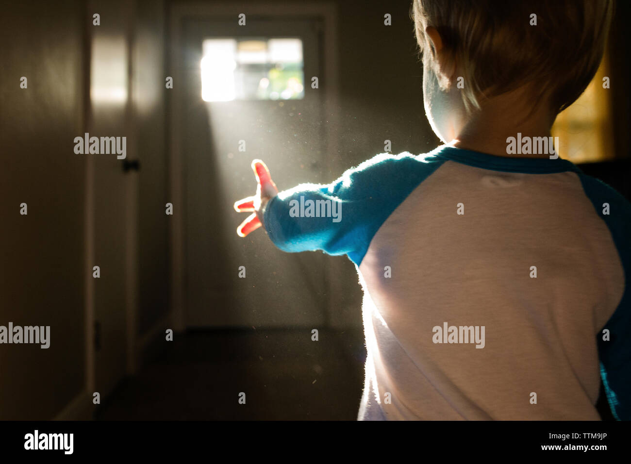 Sunlight falling on boy through door at home Stock Photo - Alamy