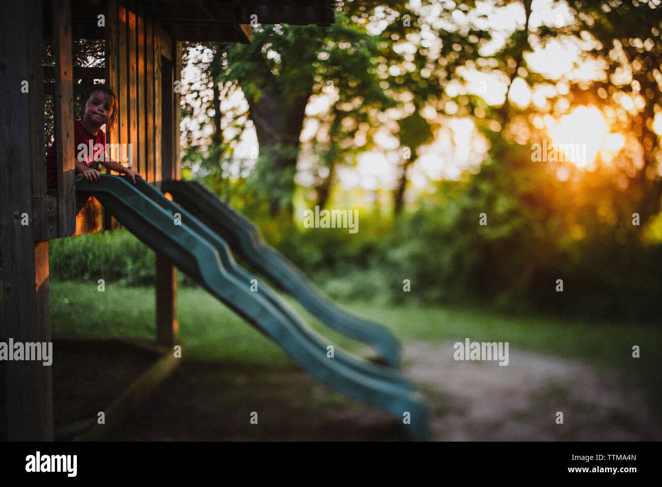 a girl smiles as she gets ready to go down a slide Stock Photo - Alamy