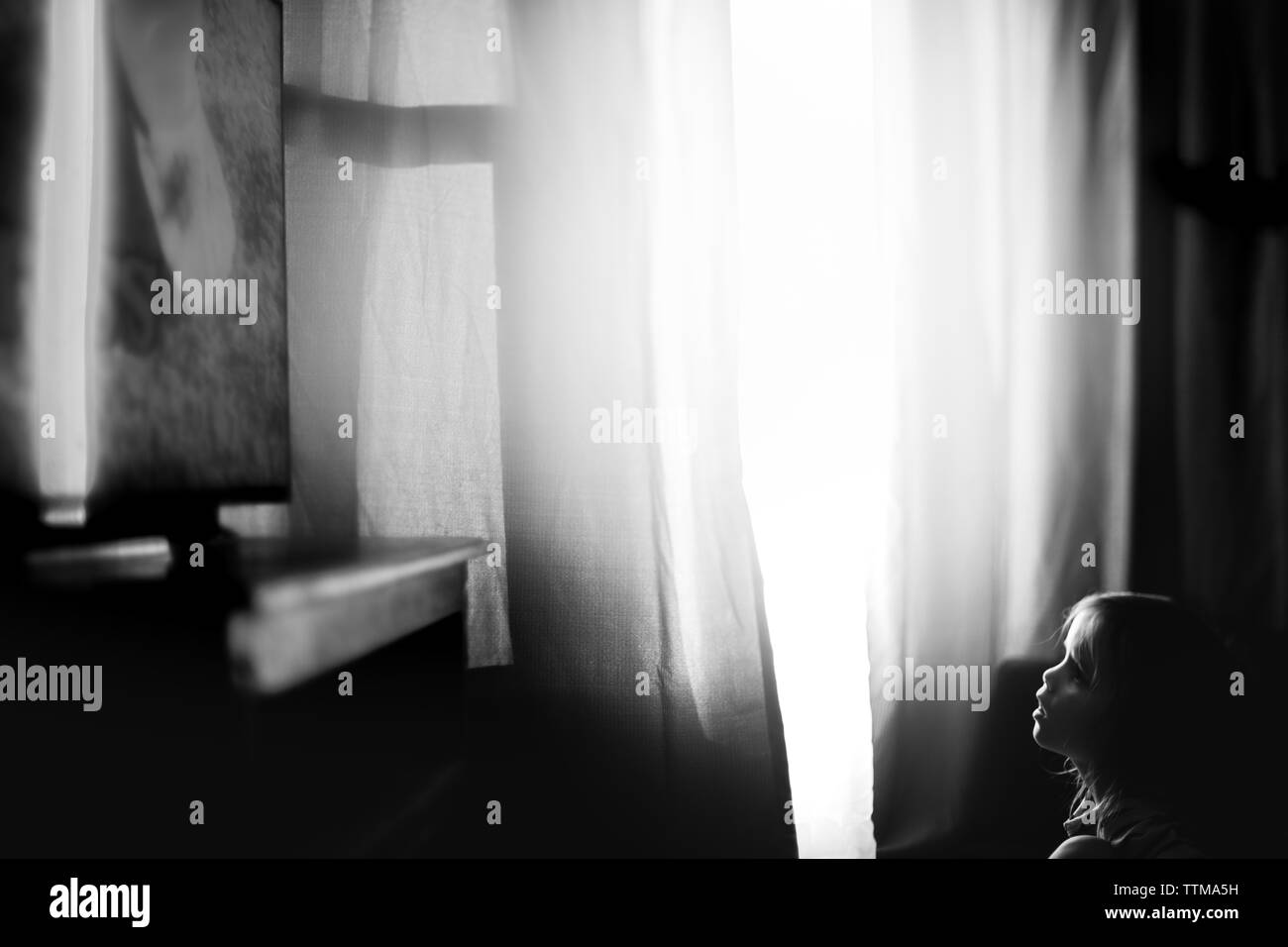 a young girl watches the tv by the window Stock Photo - Alamy