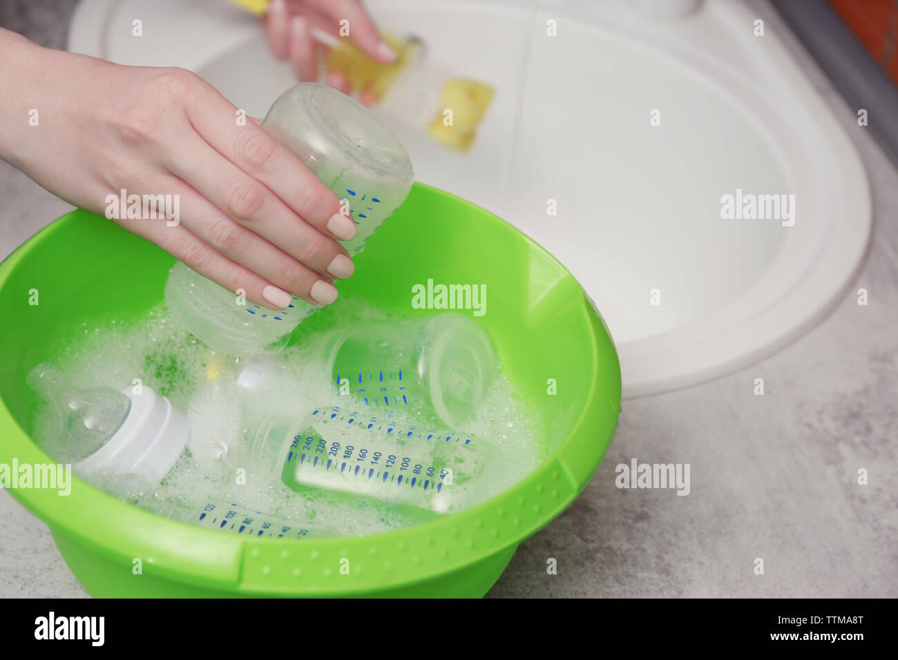 Woman hands washing baby bottles in plastic green basin Stock Photo - Alamy