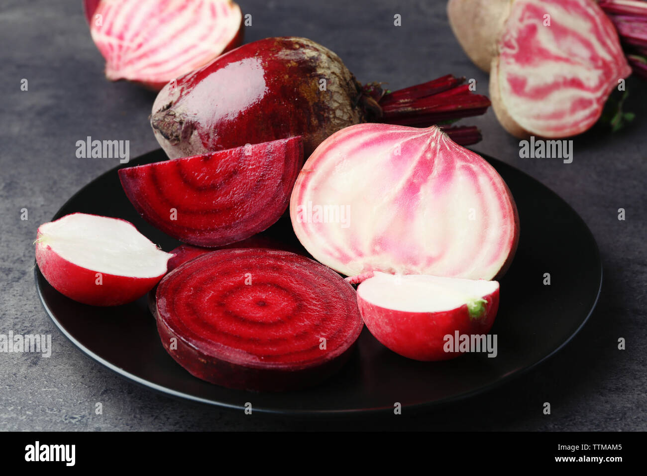Beet slices with radishes on grey table Stock Photo - Alamy