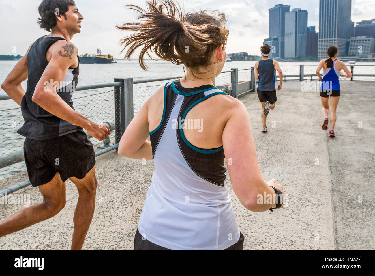 group of fit young runners playfully race each other during run workout ...