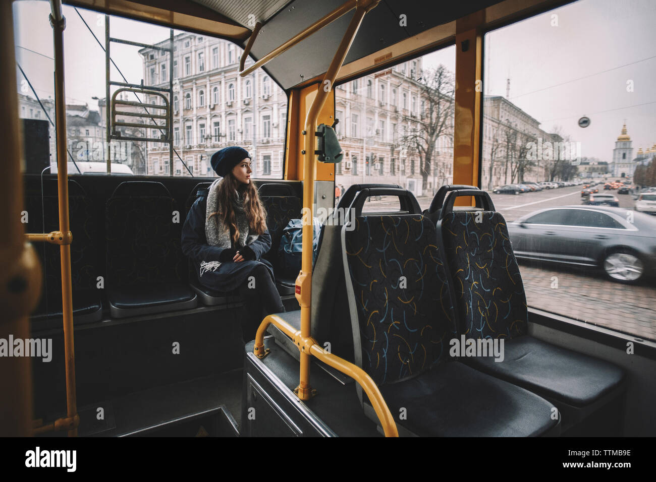 Thoughtful woman looking through window while traveling in trolley bus ...