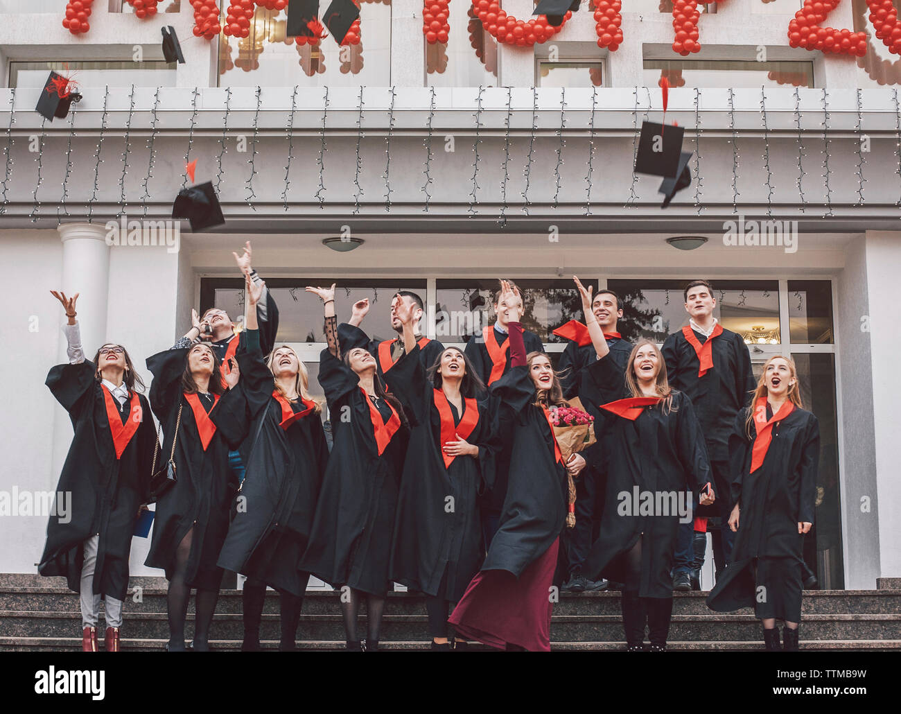 Low angle view of happy students wearing graduation gowns standing on ...