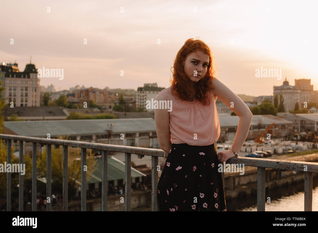 Portrait of young cute woman standing on bridge in city Stock Photo - Alamy