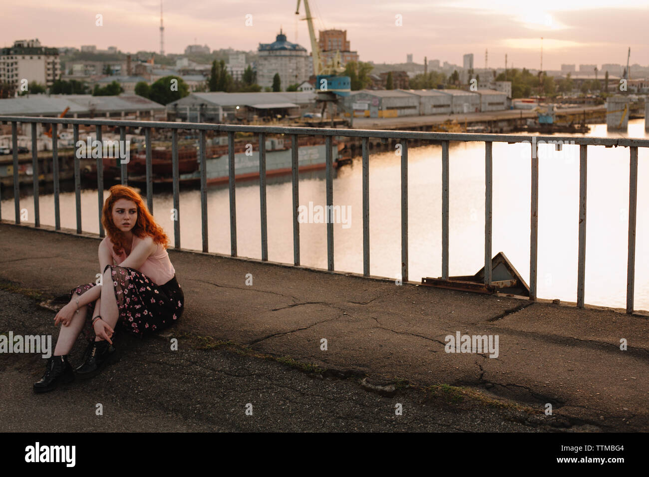 Young woman sitting on bridge in city Stock Photo - Alamy