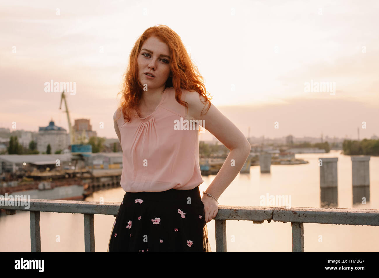 Young woman leaning on railing at bridge in city Stock Photo - Alamy