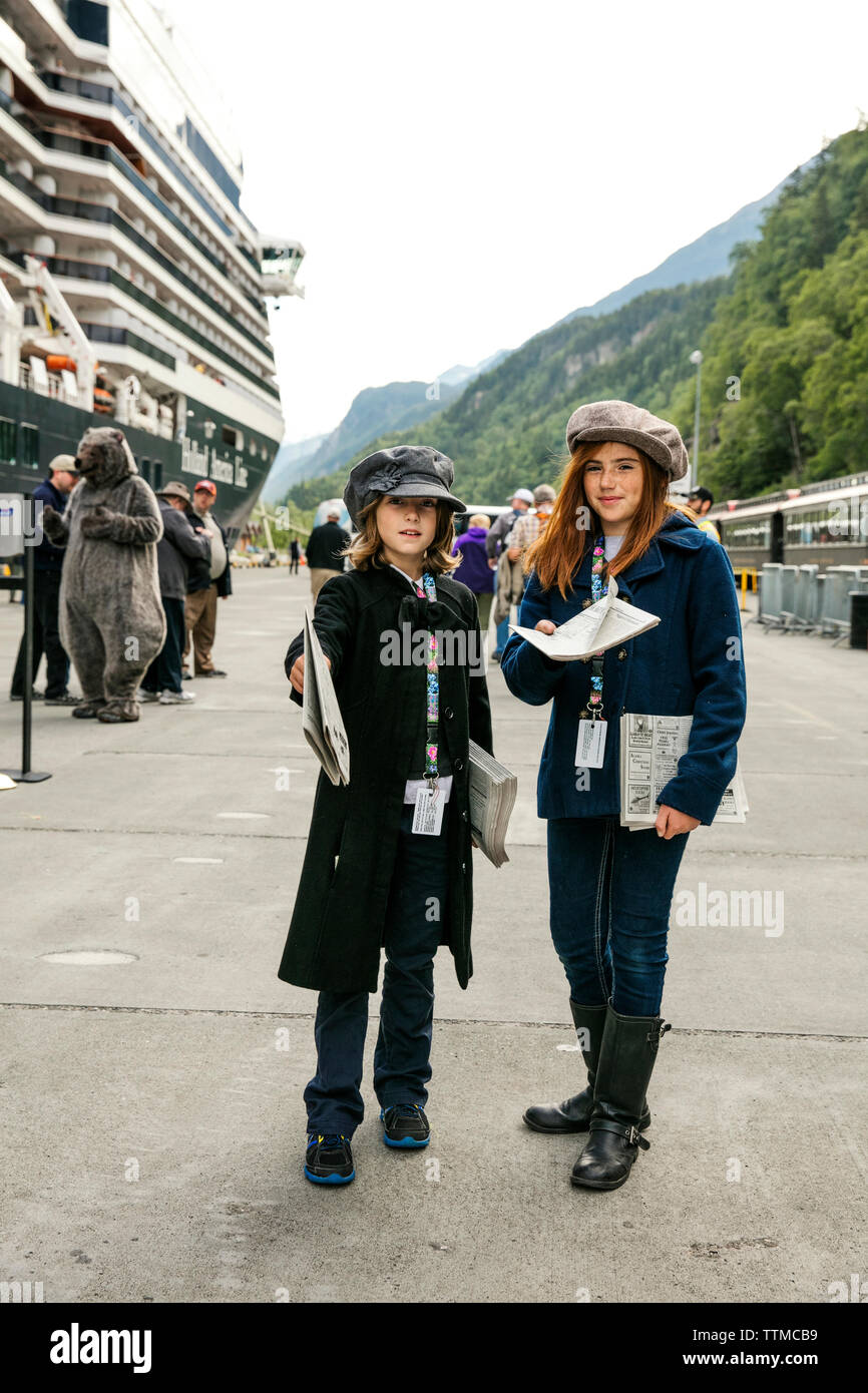 USA, Alaska, Sitka, two young girls pass out newspapers to the ...