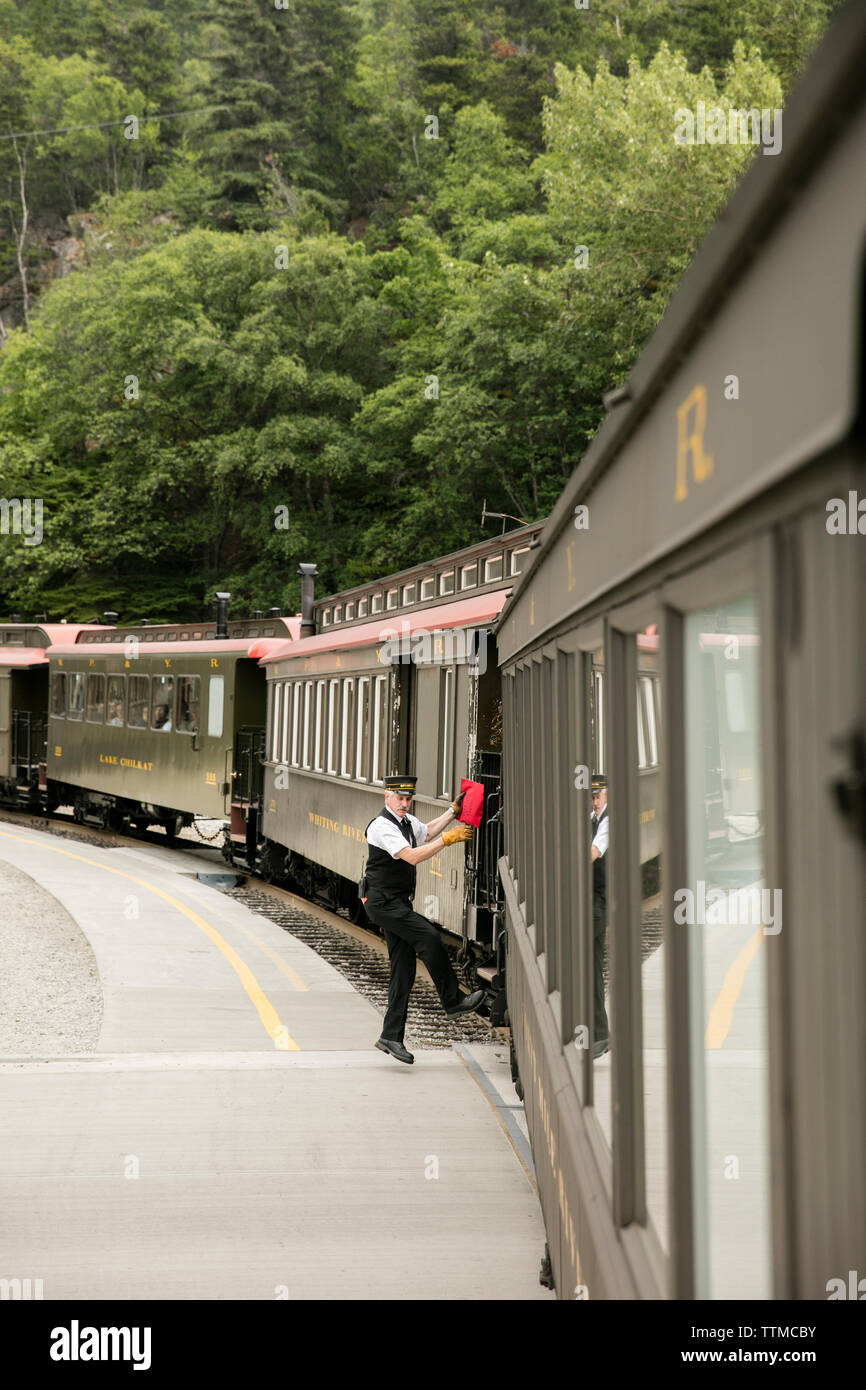USA, Alaska, Sitka, one of the train conductors climbs aboard the White ...