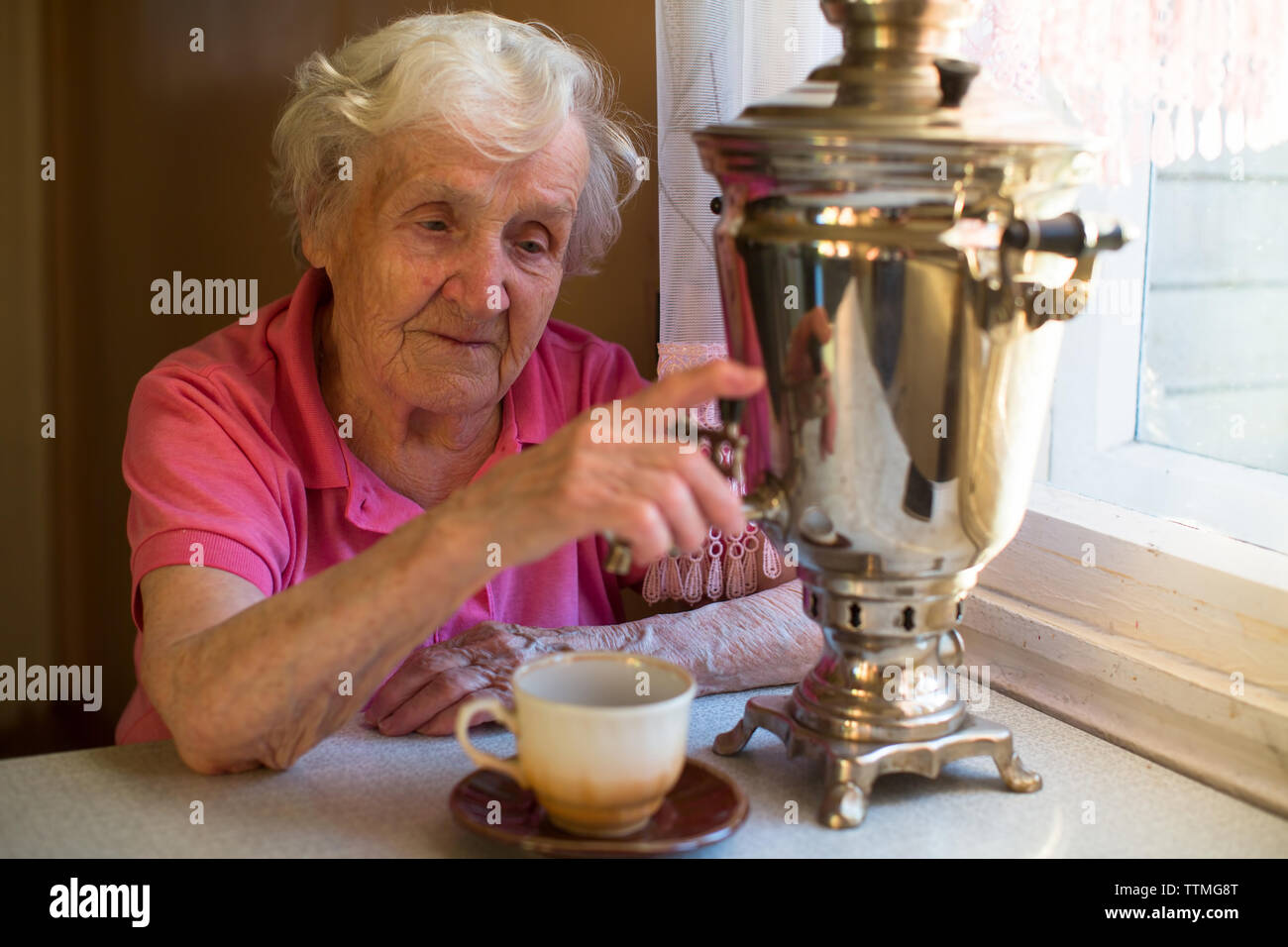 An old woman drinks tea from a Russian samovar Stock Photo - Alamy