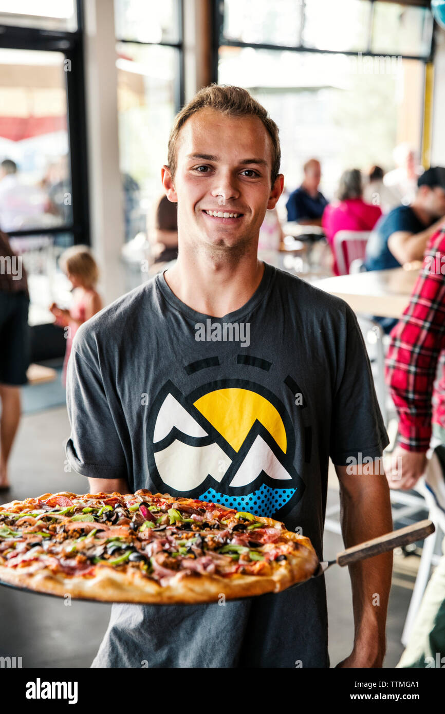 USA, Oregon, Bend, Pacific Pizza and Brew, man holding & presenting ...