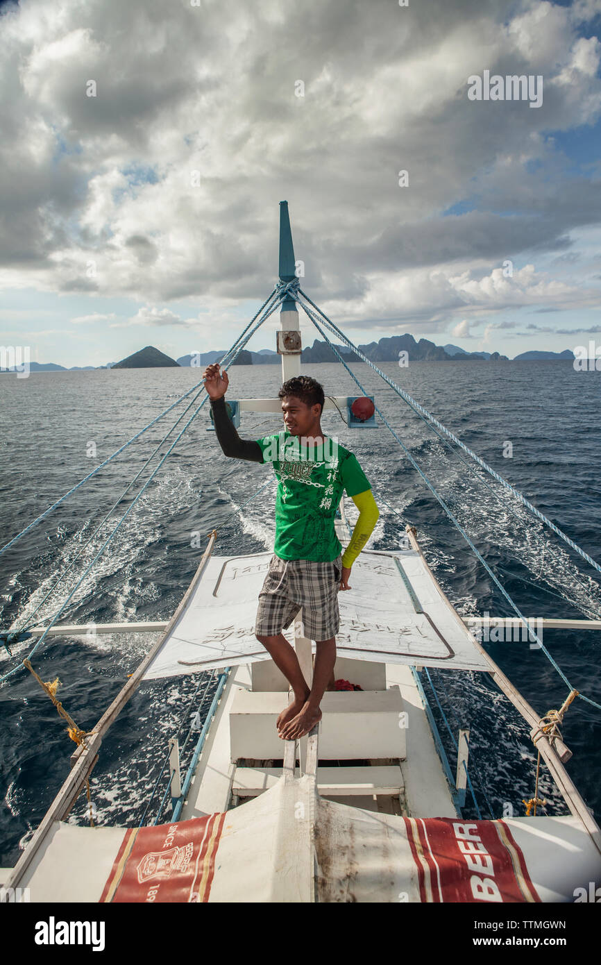 PHILIPPINES, Palawan, El Nido, Lagen Island, deck hand Eric keeps watch ...