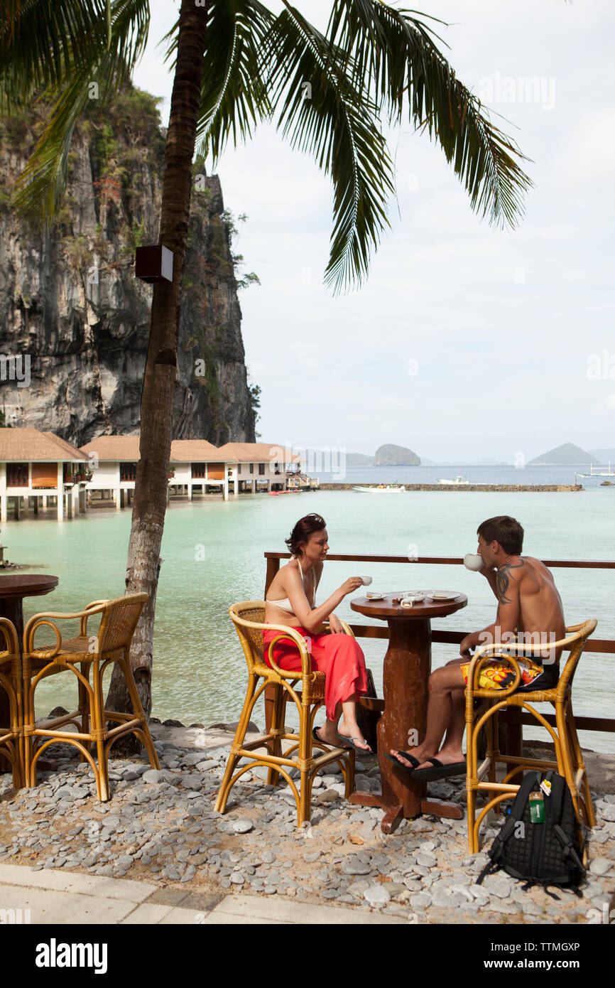 PHILIPPINES, Palawan, El Nido, Lagen Island, a couple has breakfast by ...
