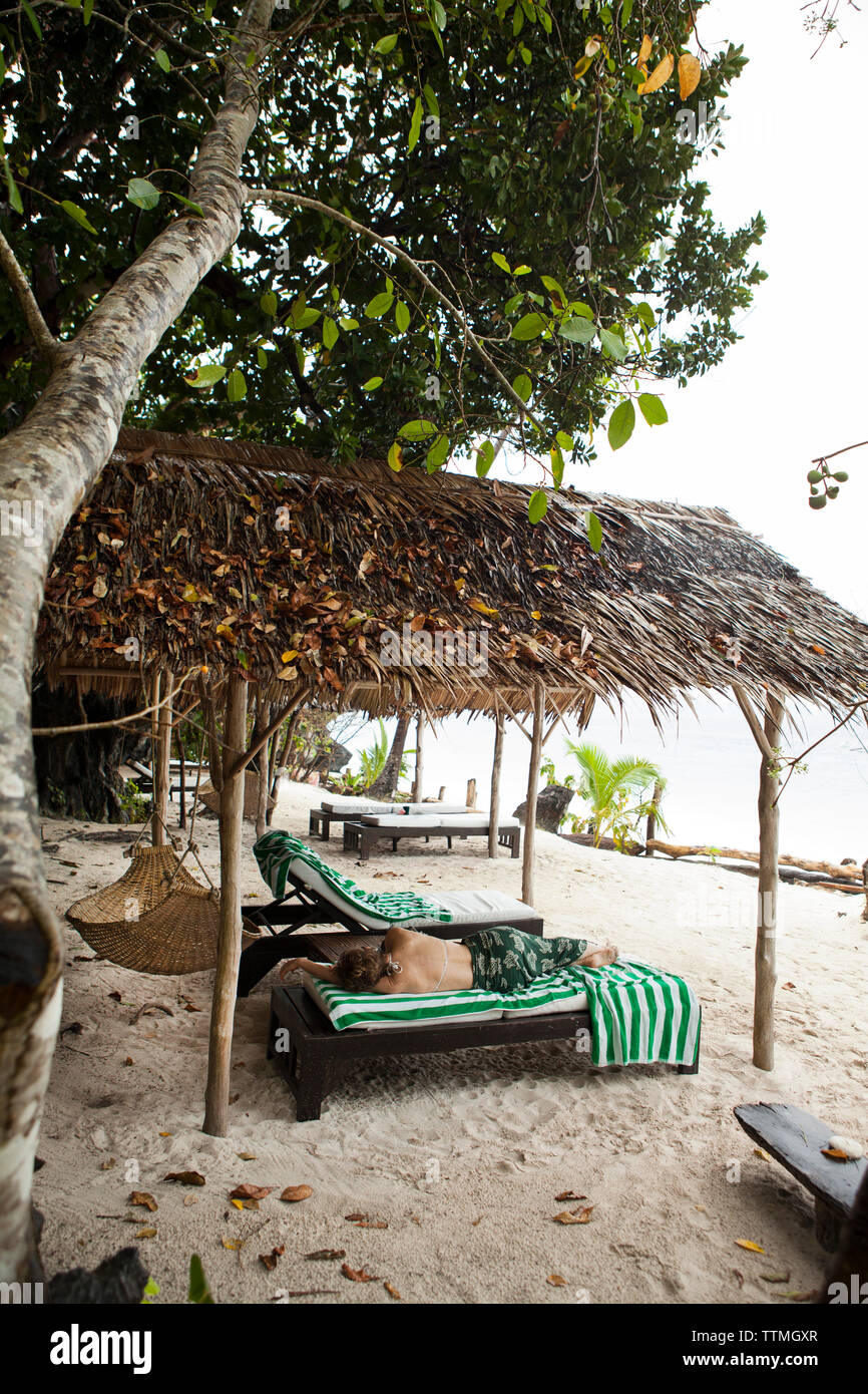 PHILIPPINES, Palawan, El Nido, Entalula Island, a woman takes a rest on ...