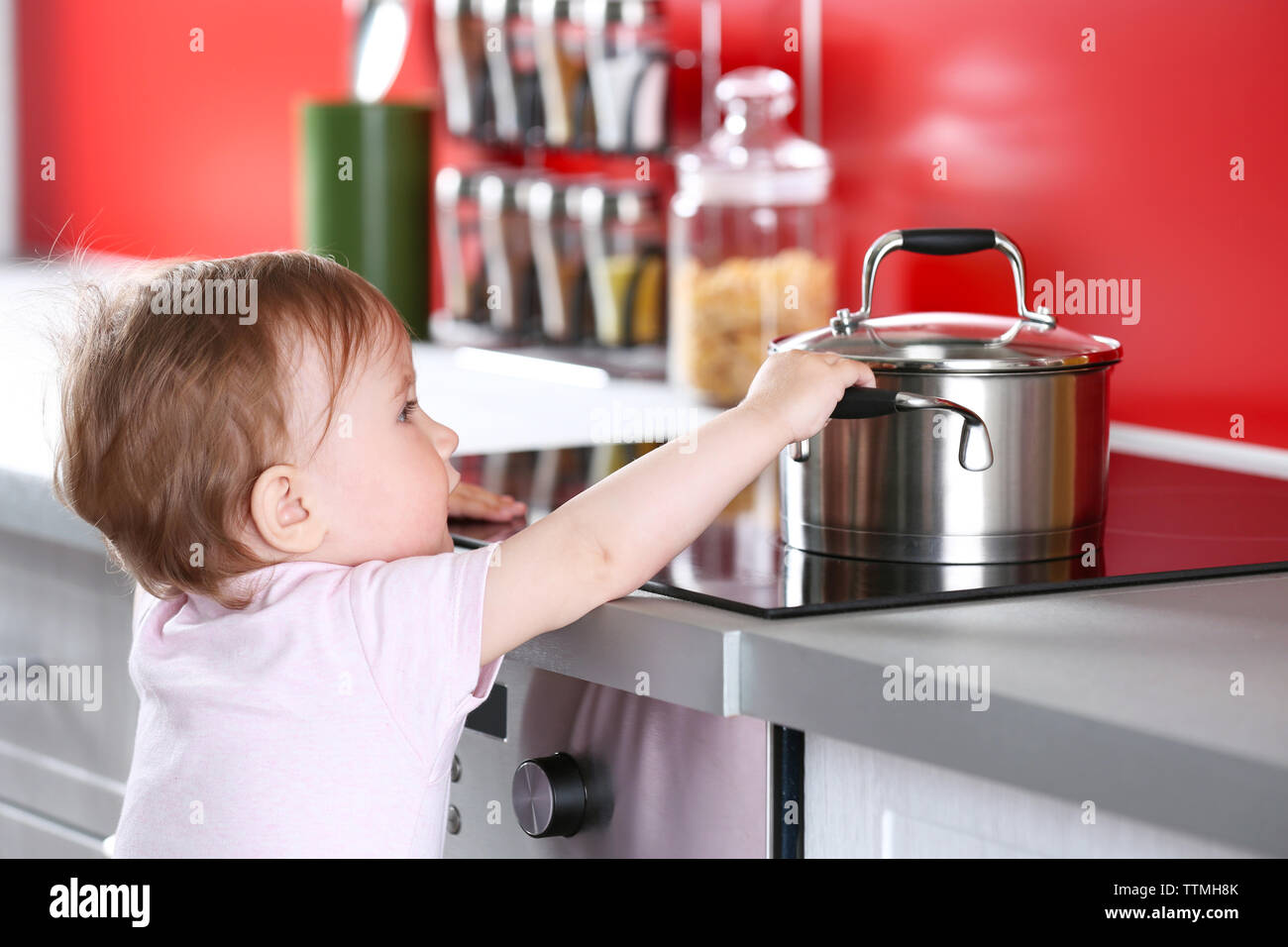 Little child playing with pan and electric stove in the kitchen Stock ...