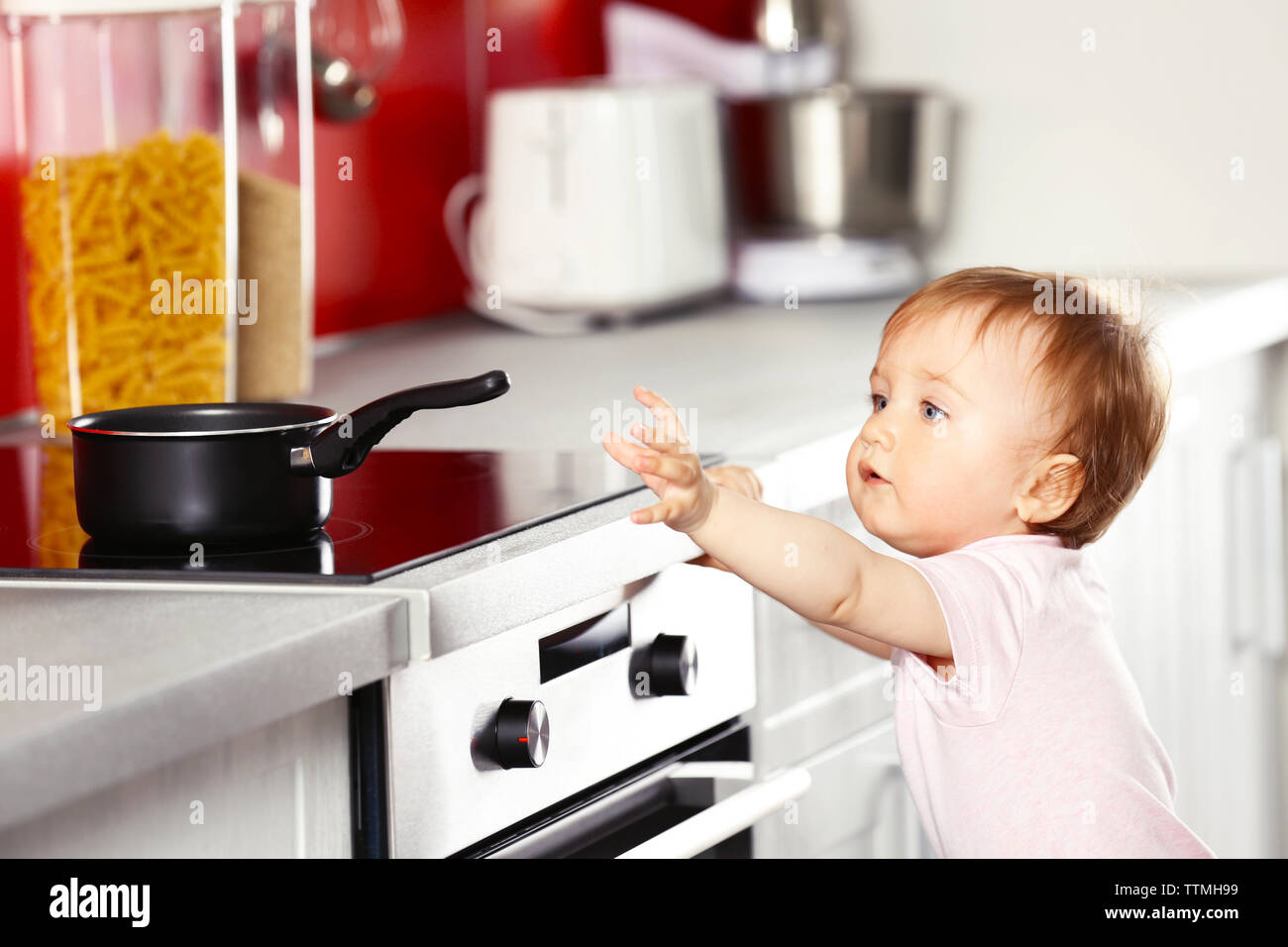 Little child playing with pan and electric stove in the kitchen Stock ...